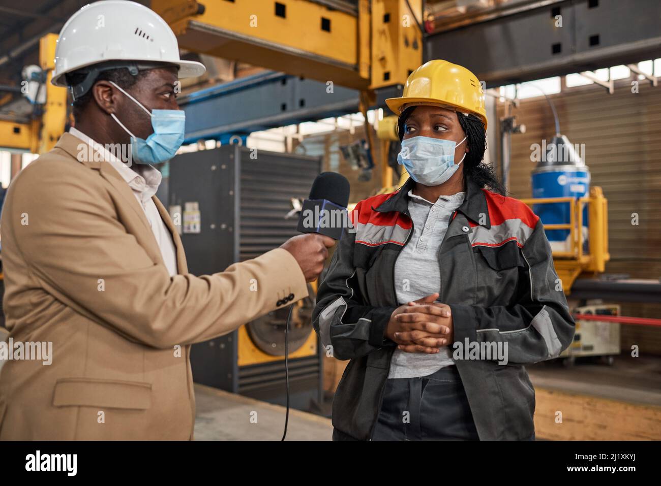 African journalist in mask interviewing the worker in uniform in ...