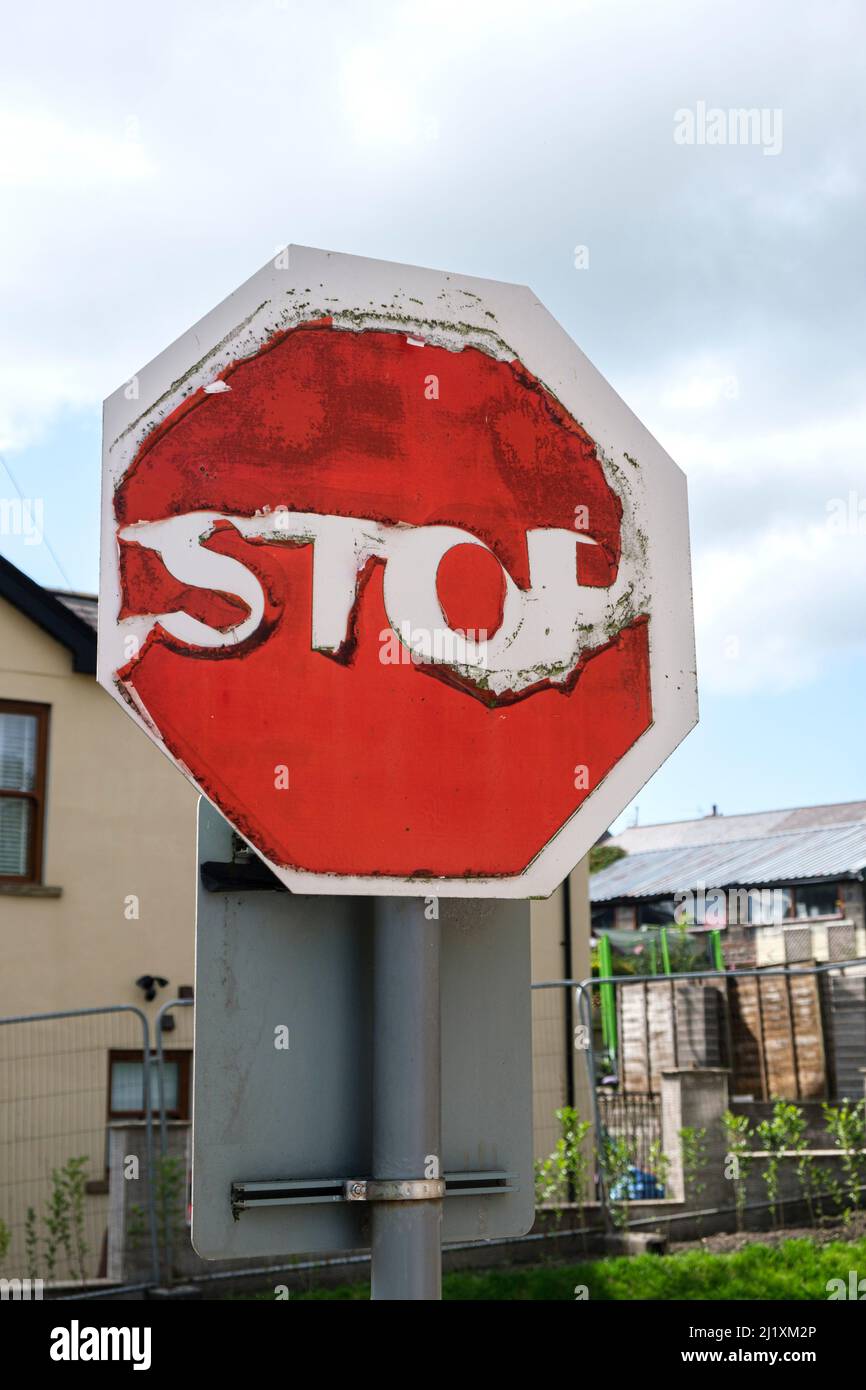 A very old weathered STOP sign with peeling paint andworn surface in ...
