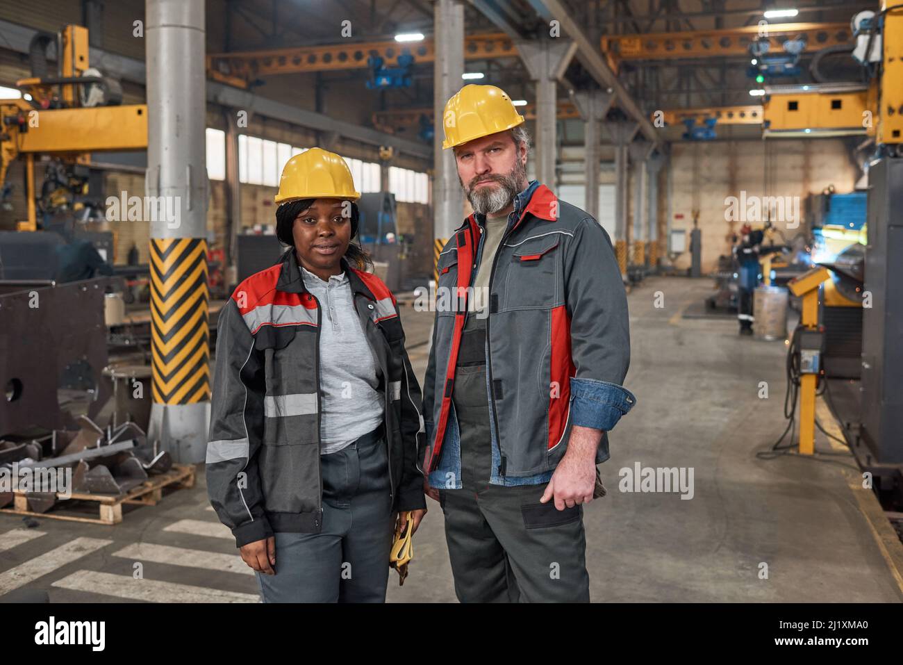Portrait of couple of workers in uniform smiling at camera while ...