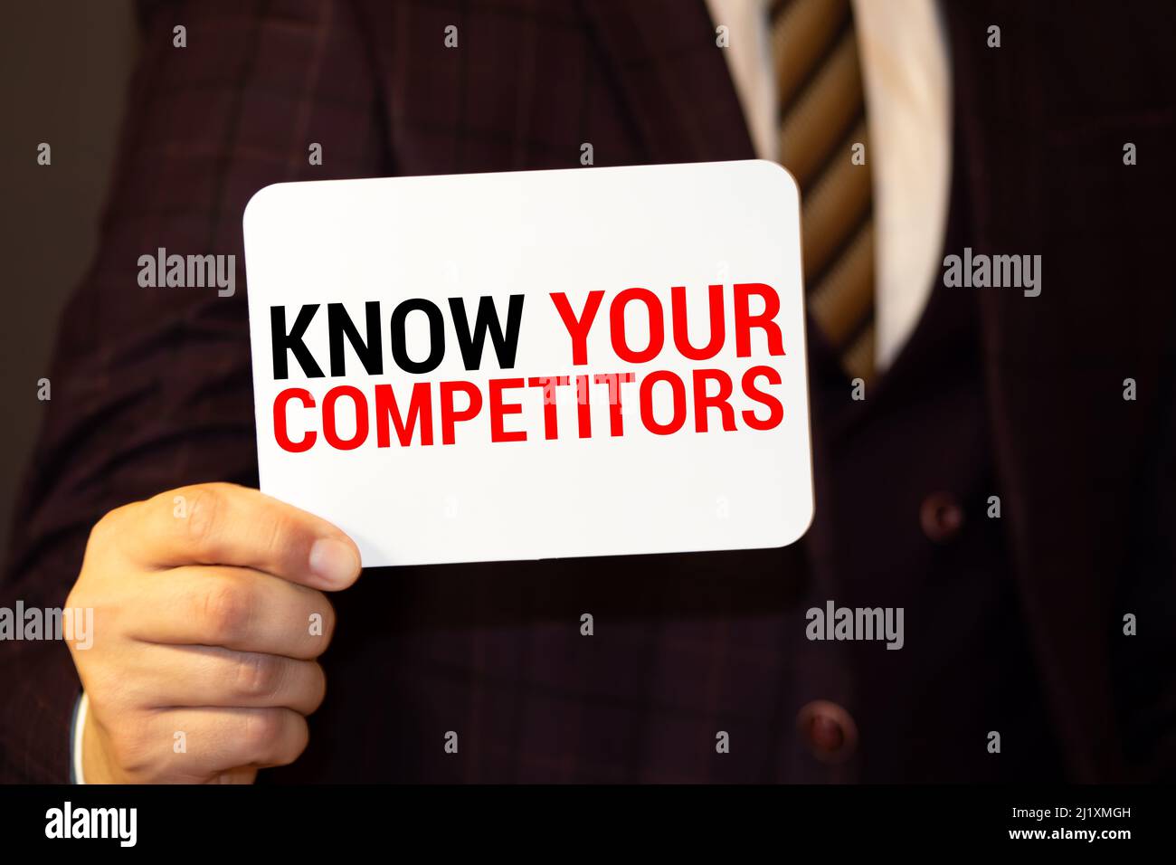 Businessman putting a card with text KNOW YOUR COMPETITORS in the ...