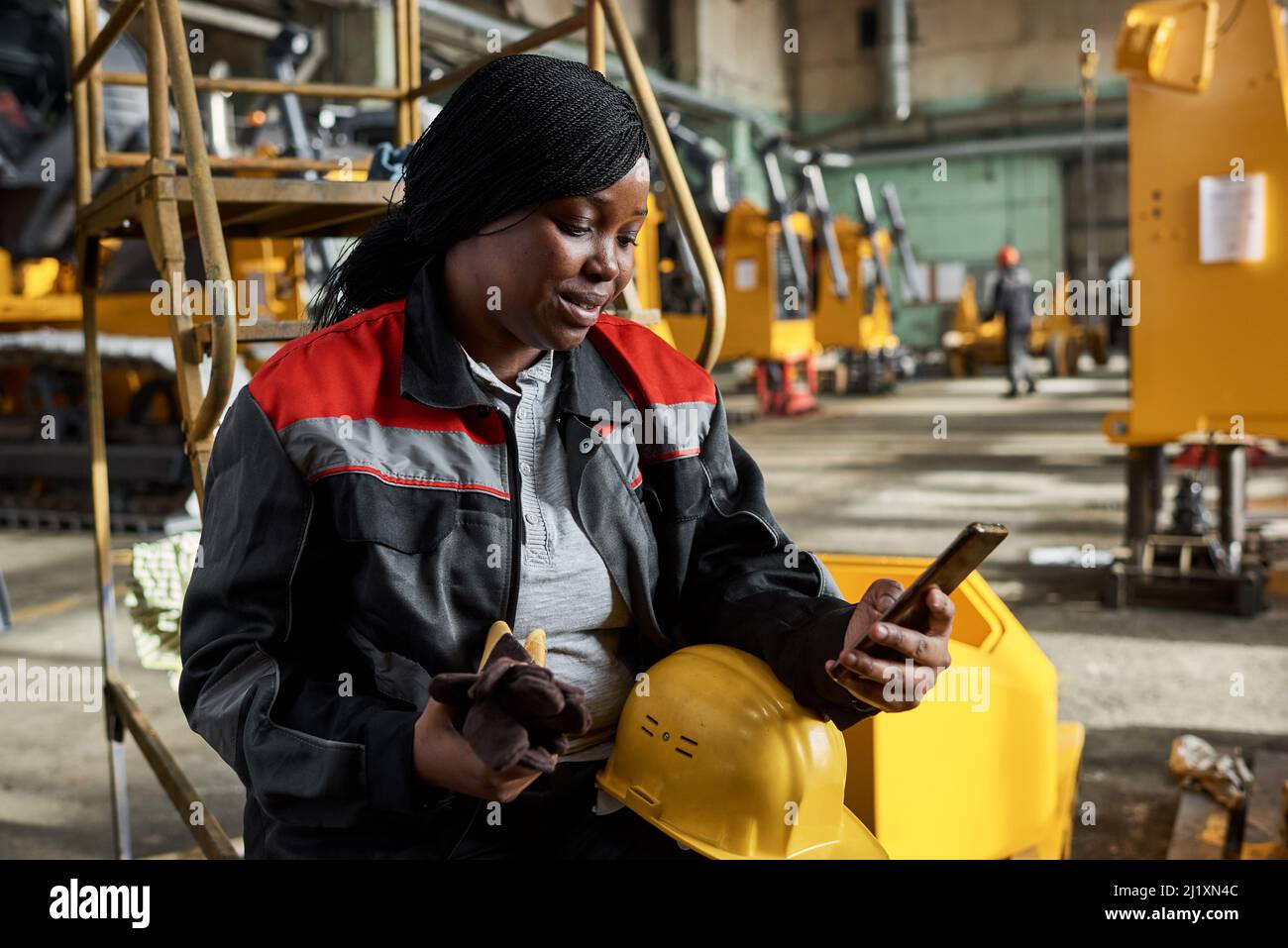 African female worker in uniform reading a message on mobile phone ...