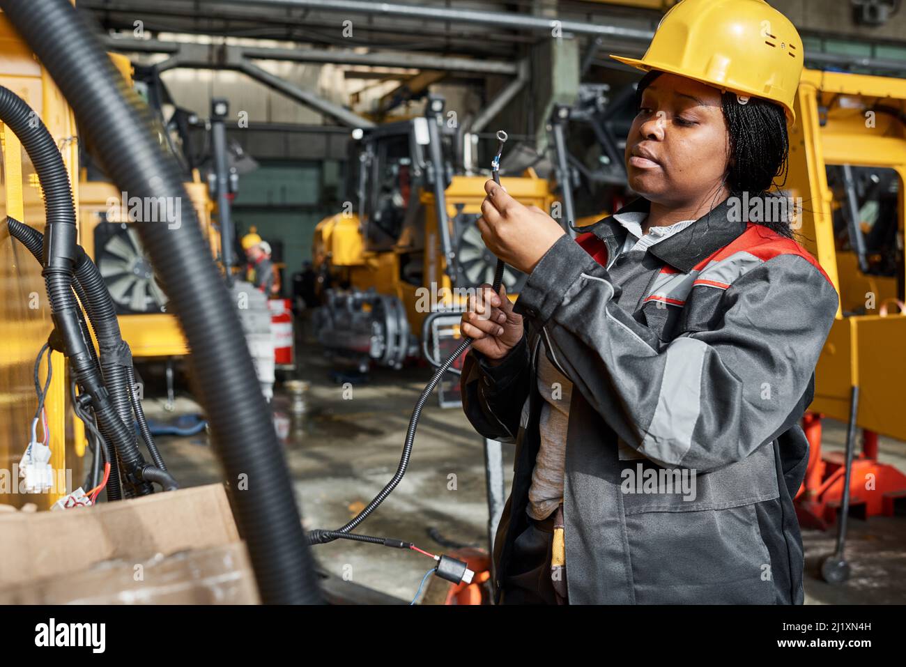 African female worker in uniform connecting wires to equipment during ...
