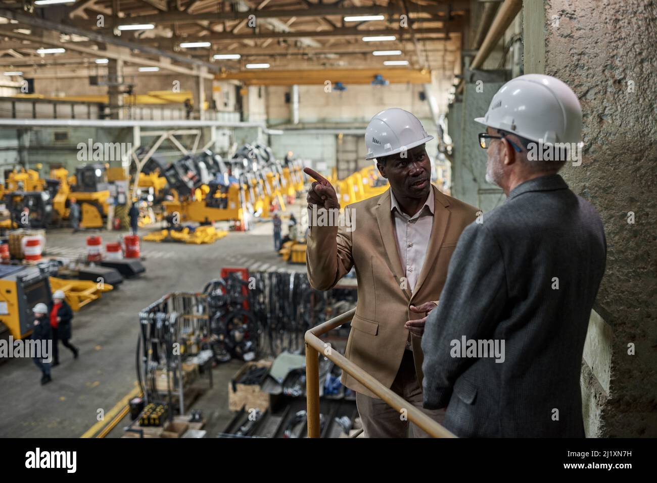 Two engineers in suit and work helmet standing on the top floor and ...