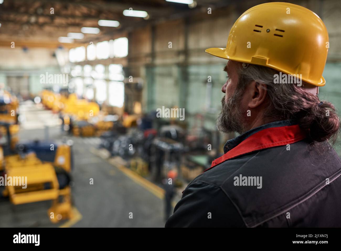 Rear view of foreman in hardhat watching for the process in factory ...