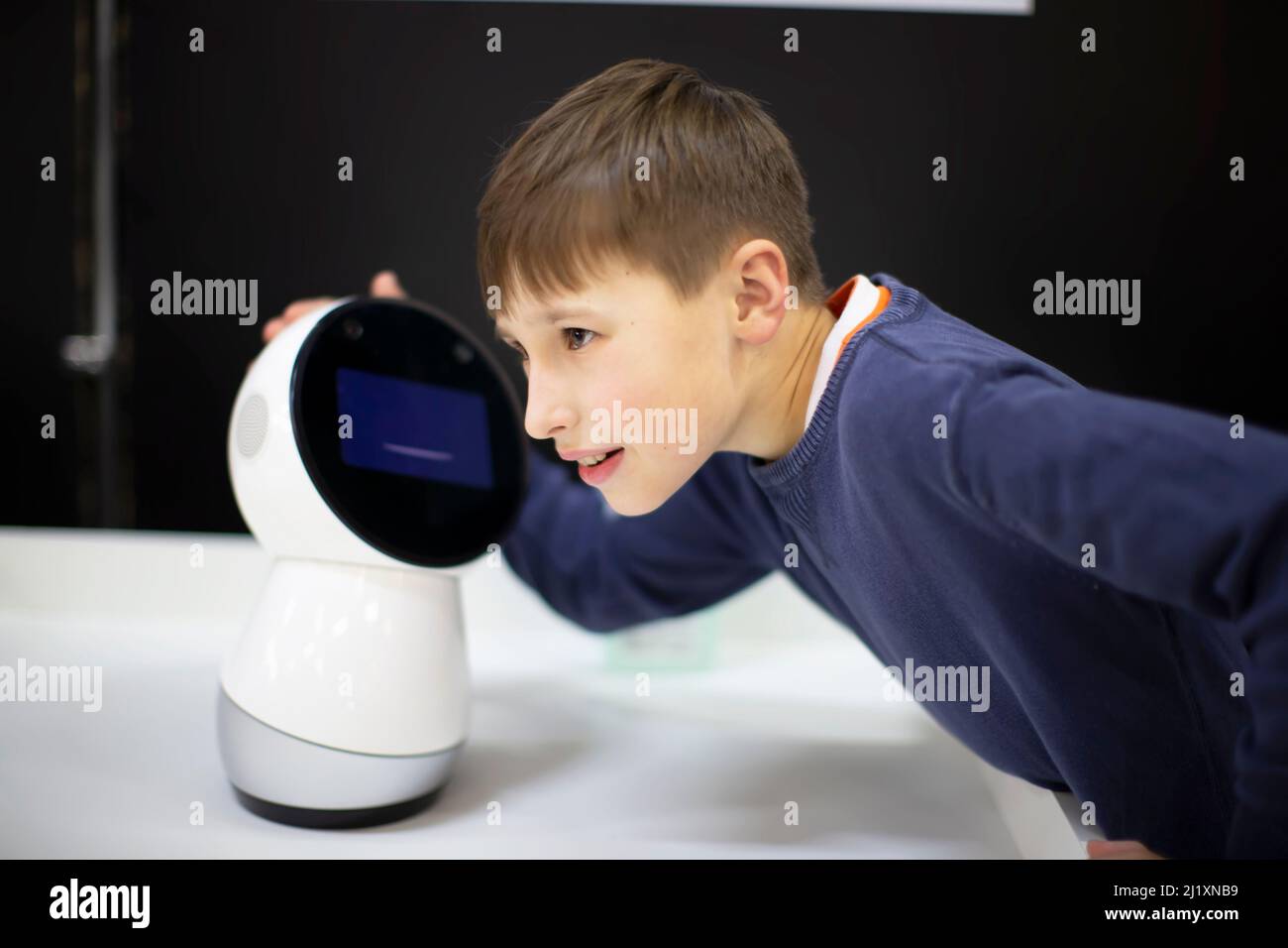 Boy talking, playing with android robot at the exhibition Stock Photo ...