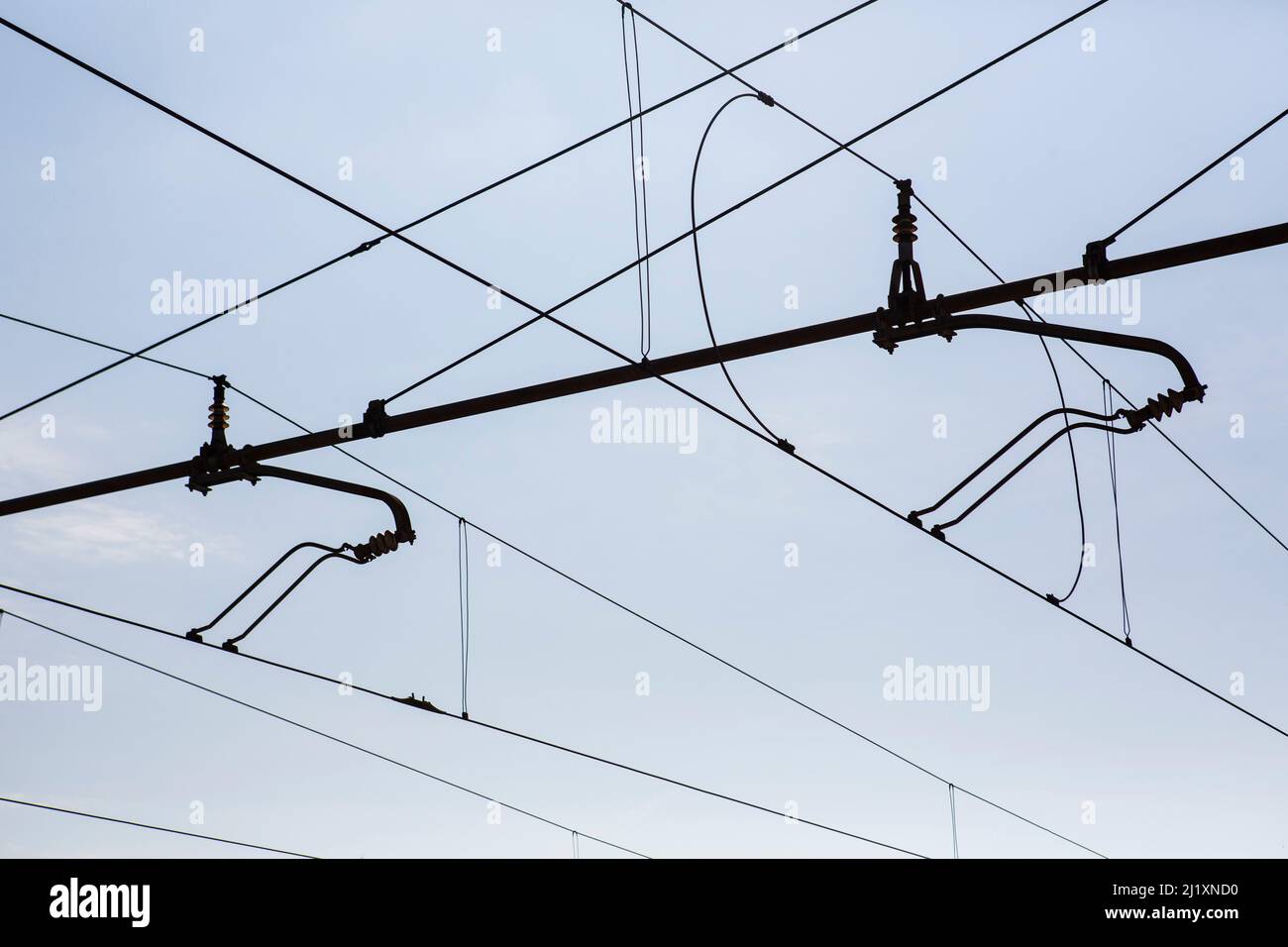 Overhead wires criss cross the blue sky providing power to elctric ...