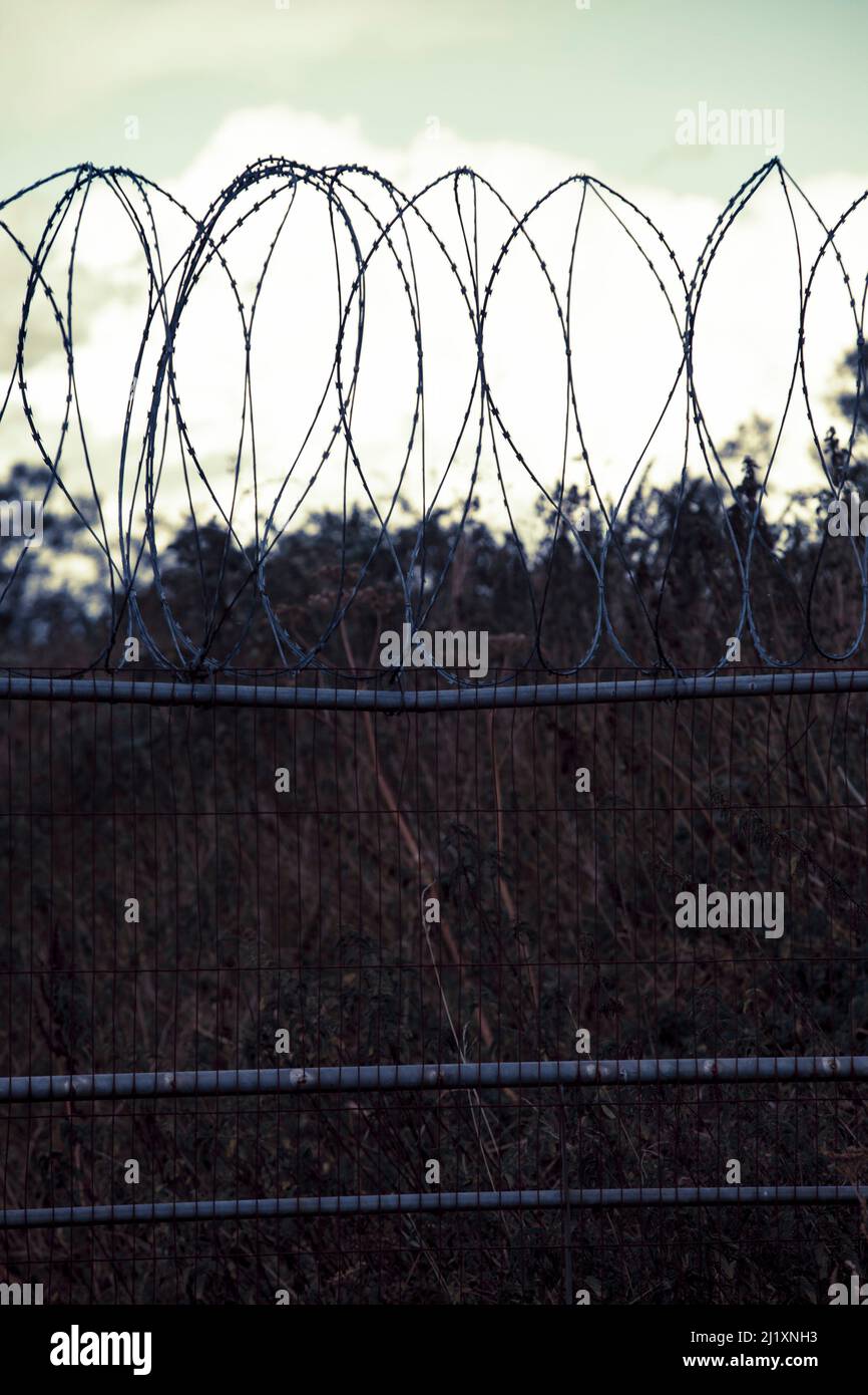 A high security fence with razor wire and barbed wire across the top ...