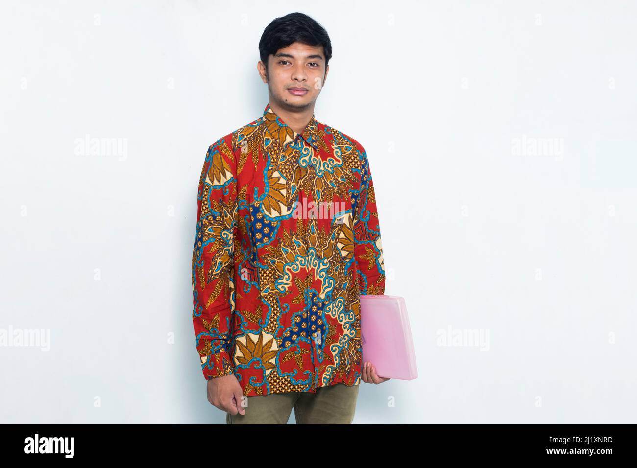 asian young man wearing batik confident while holding a pink envelope ...