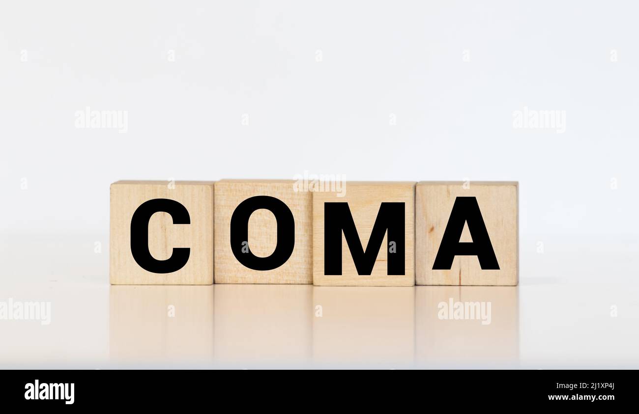 word coma made from gray wooden letters lies on a green background ...