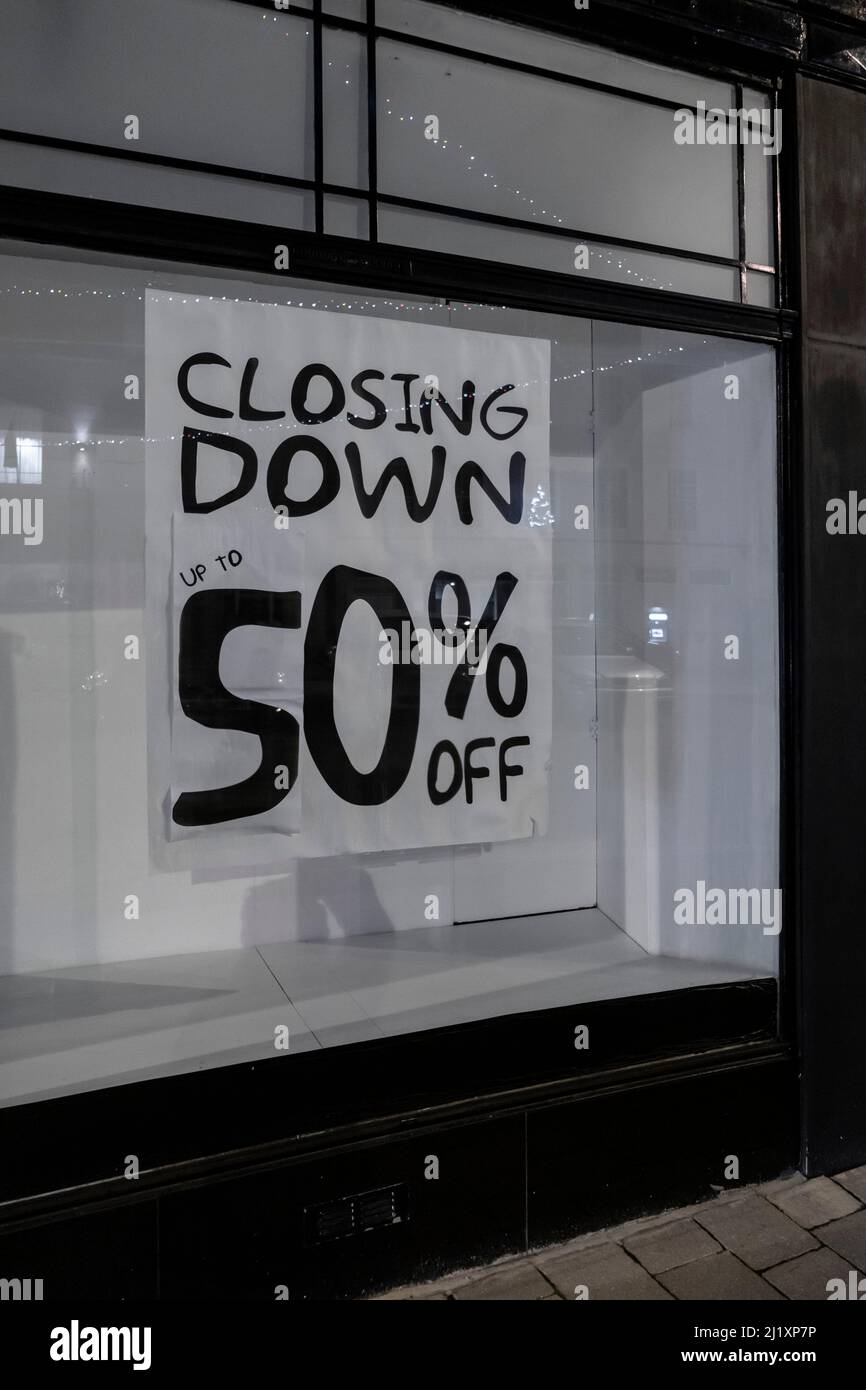A dark night in town with a shop front dispalying a poster announcing a ...