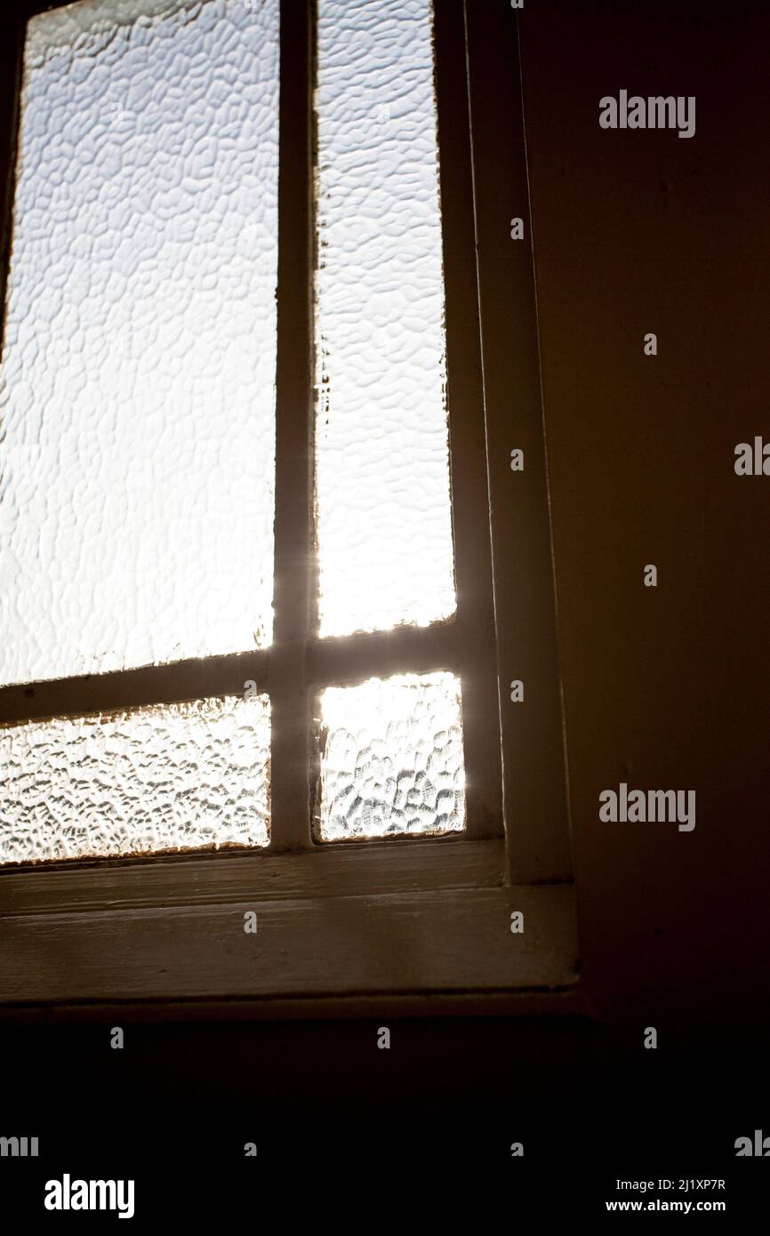 Bright sunlight shining through a pane of textured glass obscuring the ...