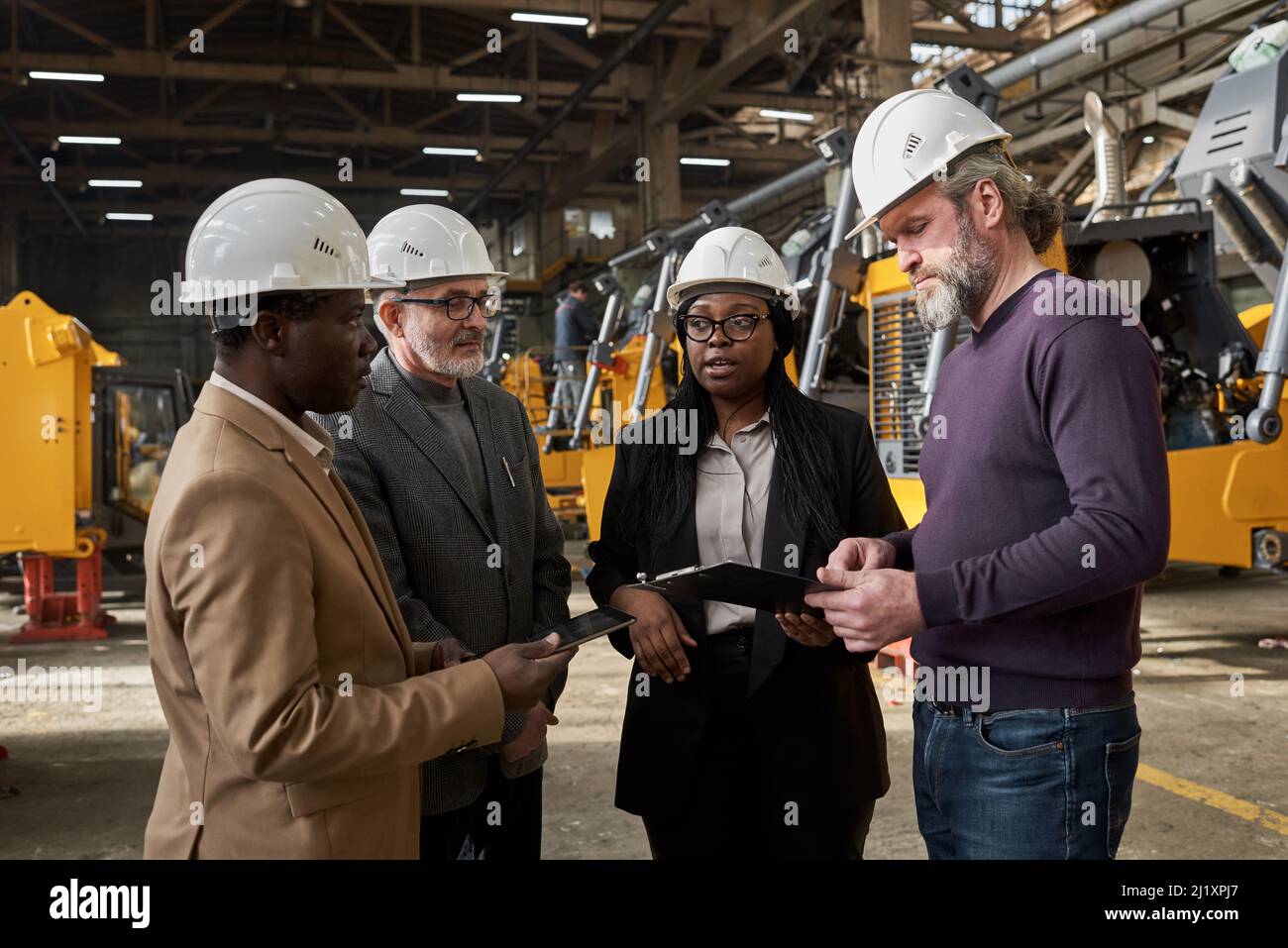 Group of business people in work helmets discussing the supply of new ...