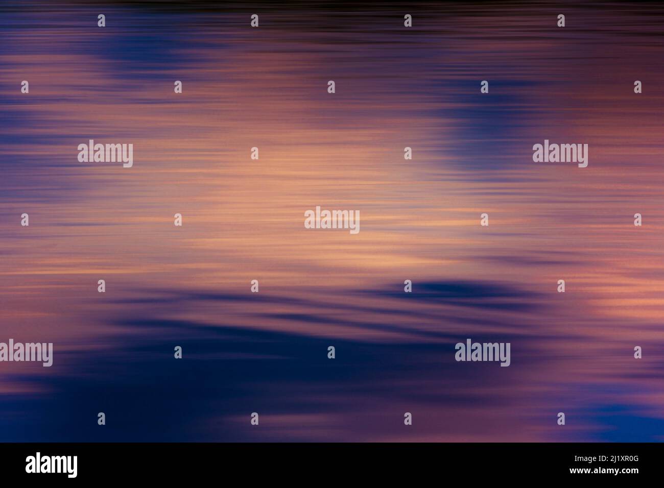 Small waves and ripples reflecting the colourful sky on the surface of ...