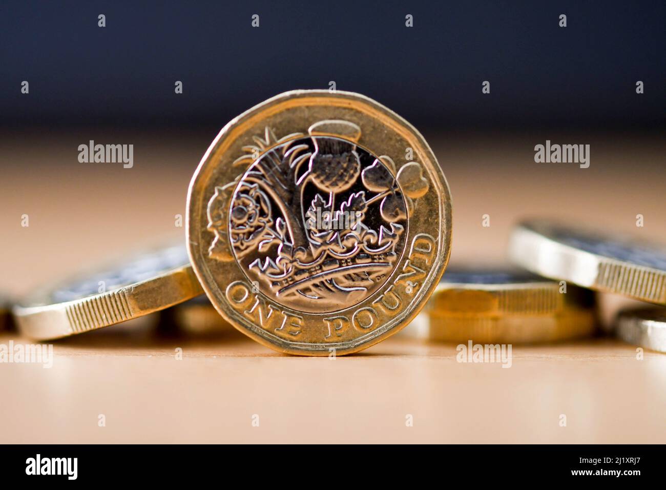British one pound coin standing on its edge with other coins in the ...
