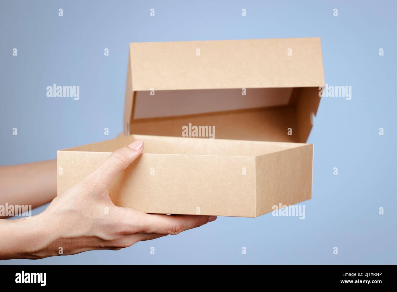 Female hands opening brown cardboard box on light blue background ...