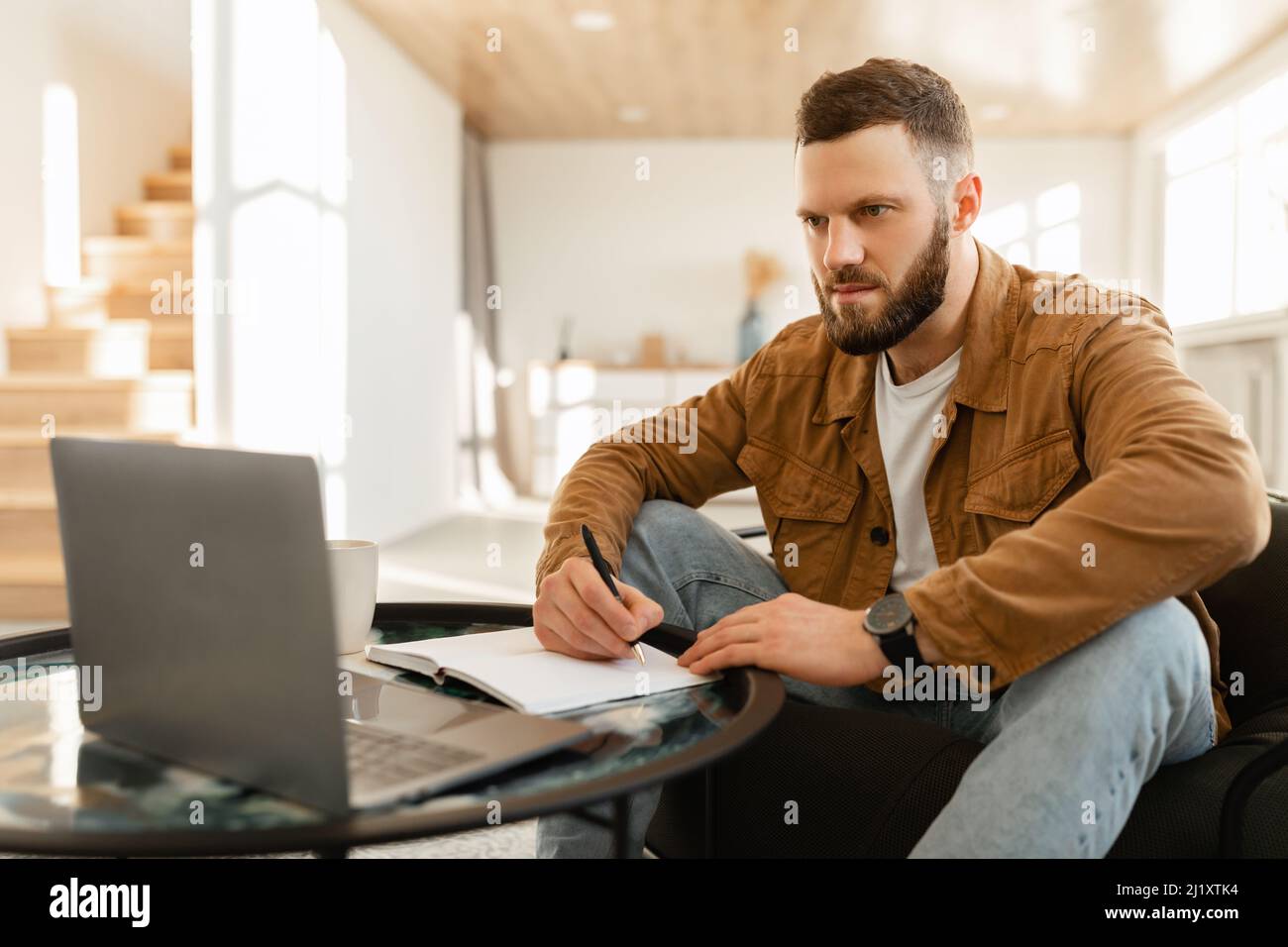 Side View Of Man Taking Notes And Using Laptop Indoor Stock Photo - Alamy