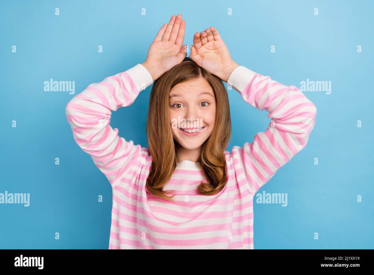 Portrait of positive childish person arms make ears toothy smile look ...