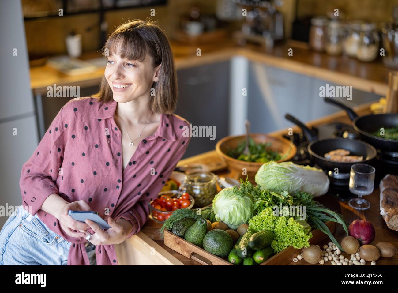 Woman using smatphone while cooking healthy at home Stock Photo - Alamy