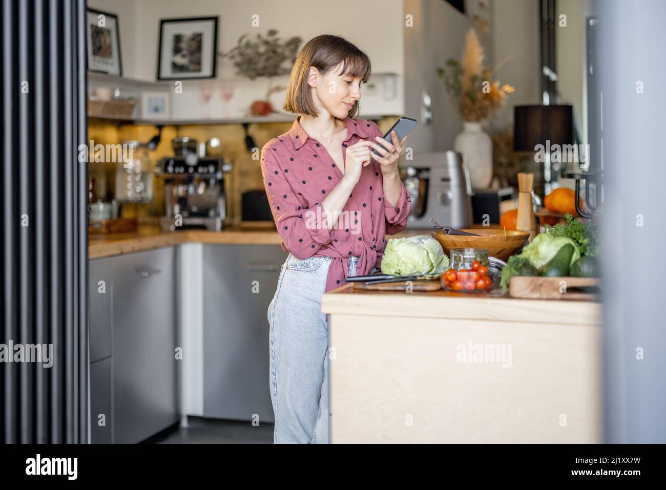 Woman using smatphone while cooking healthy at home Stock Photo - Alamy