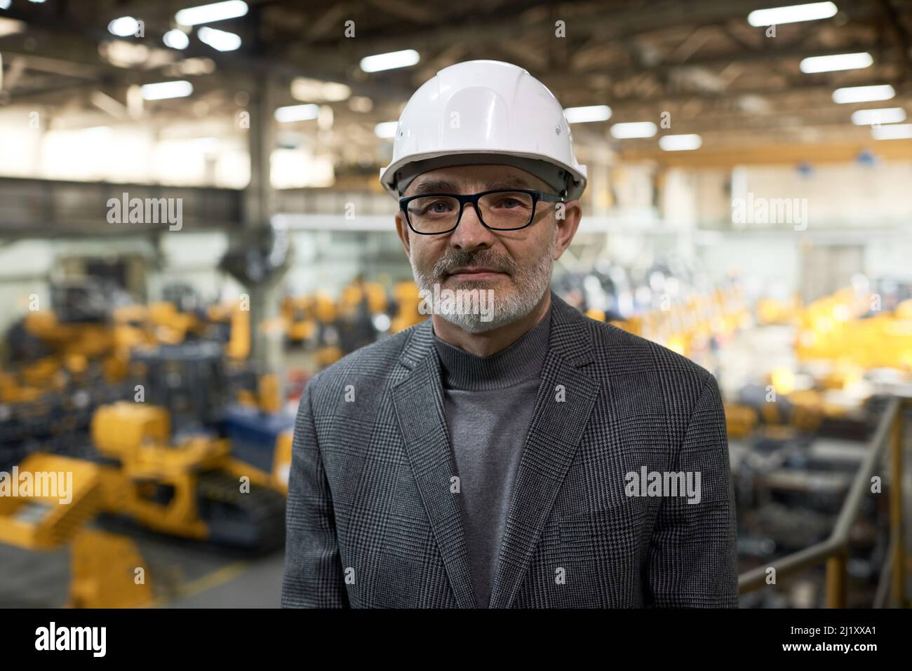Portrait of elder engineer in hardhat looking at camera while running ...