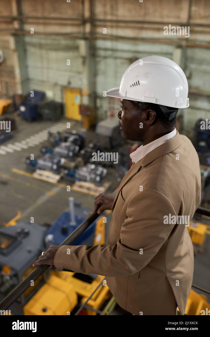 African engineer in work helmet standing on balcony on top floor and ...