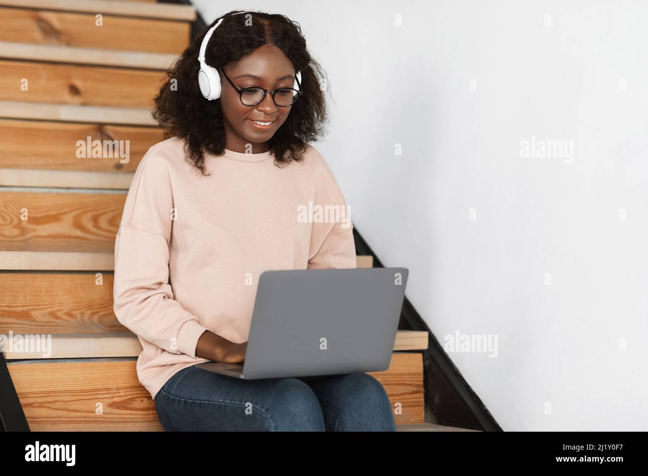 African American Female Typing On Laptop Wearing Headphones At Home ...