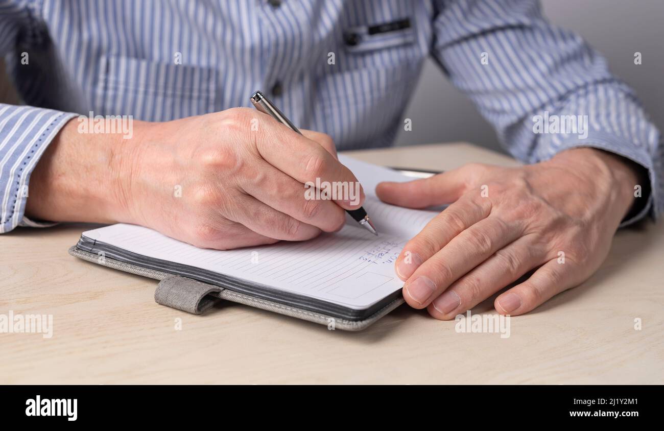Man hands closeup taking notes in planner. Student or employee writing ...