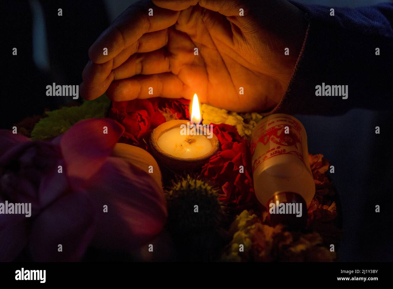 A close-up shot of an adult hand covering a lighting candle among the ...
