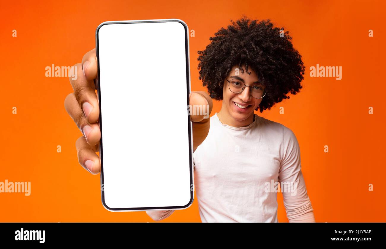 Happy black guy demonstrating smartphone with big blank white screen ...