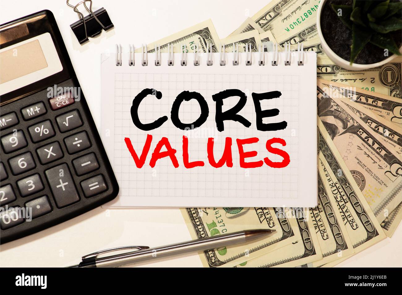 Notebook with text inside Core Values on table with coffee, laptop and ...