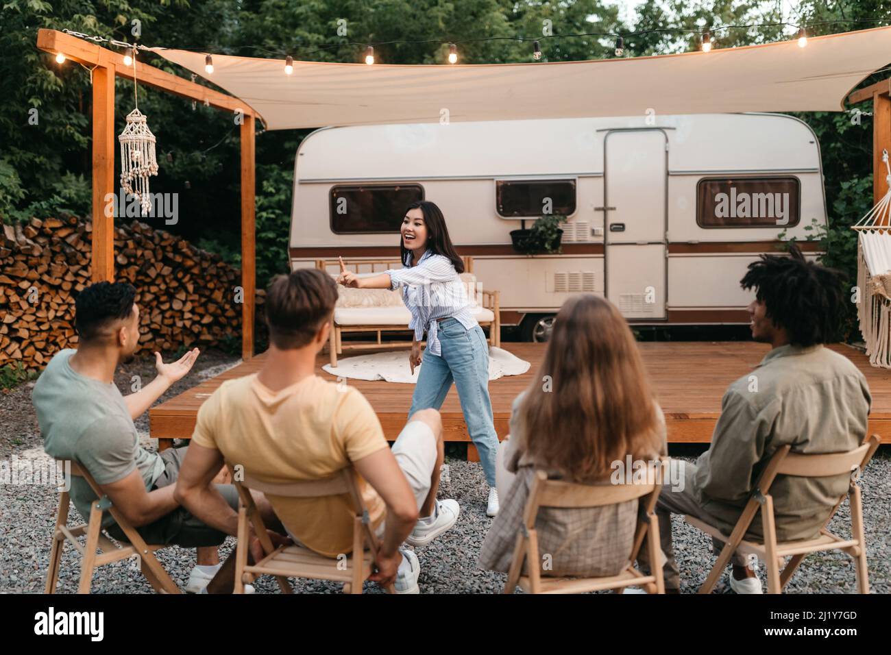 Happy Asian lady playing word guessing game with diverse friends near ...