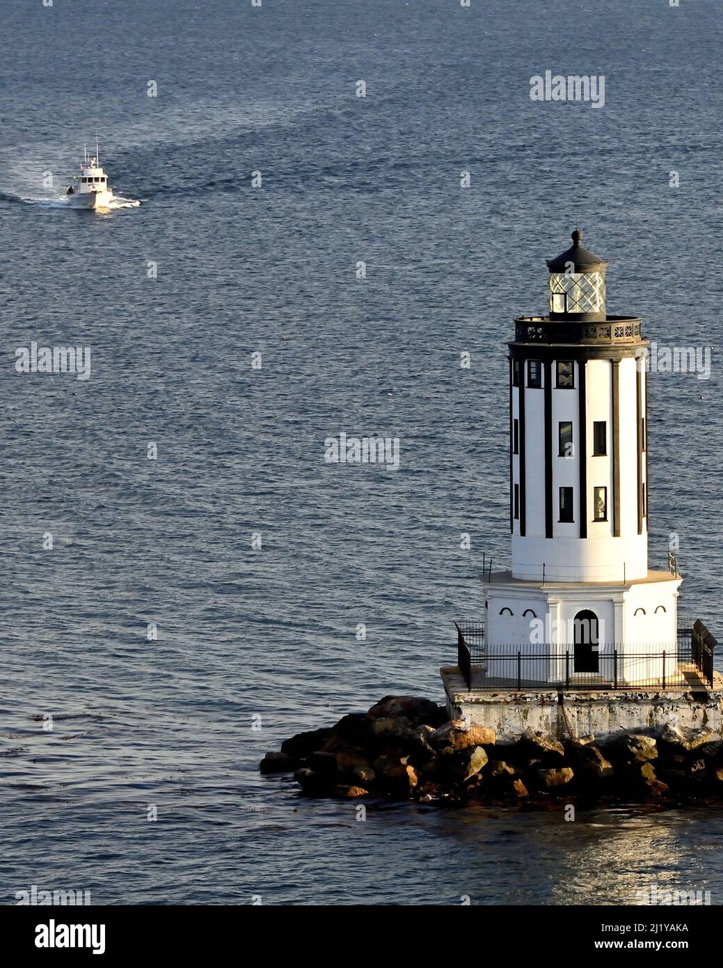 A bird's eye view of a boat sailing to a lighthouse on a stone pier ...