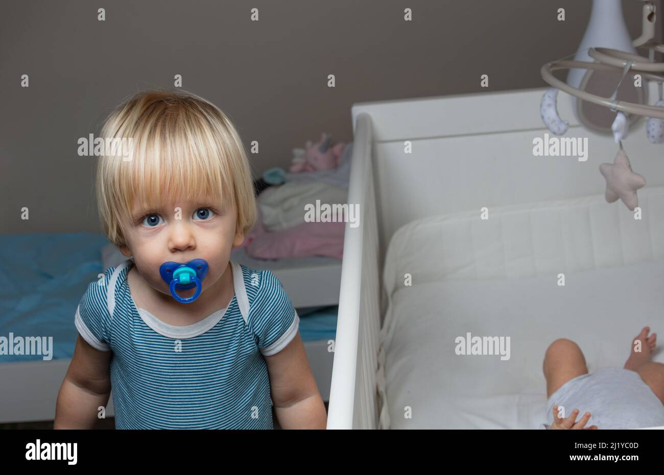 Little blond boy stand near the crib of newborn baby Stock Photo - Alamy
