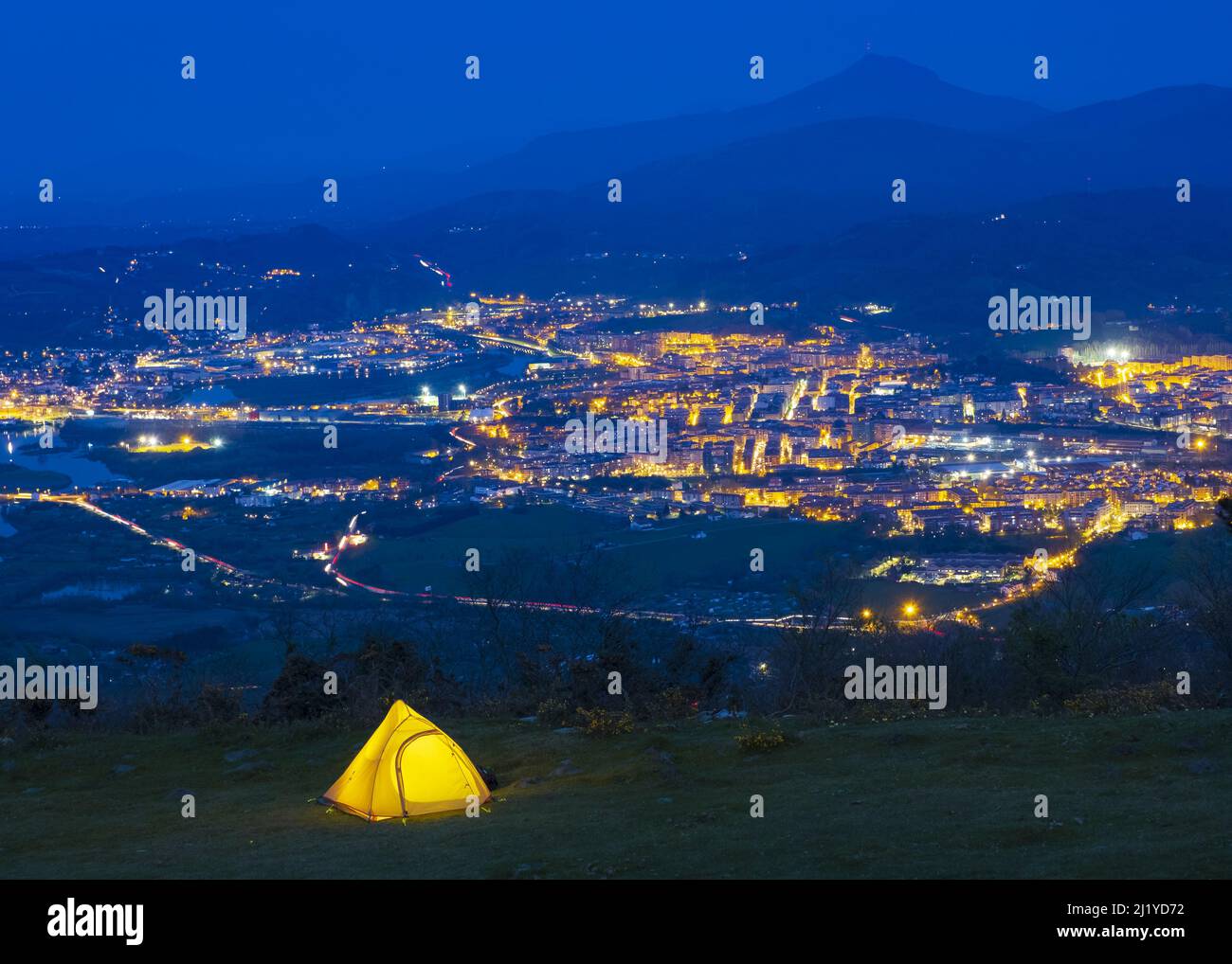 camping tent at night with the lights of the city in the background ...