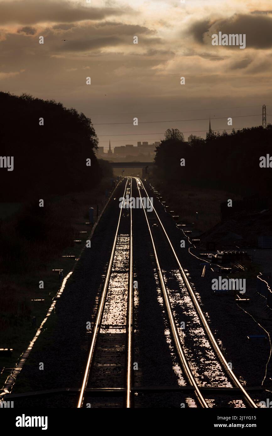 Low early morning winter sunlight glinting off the two track railway at ...