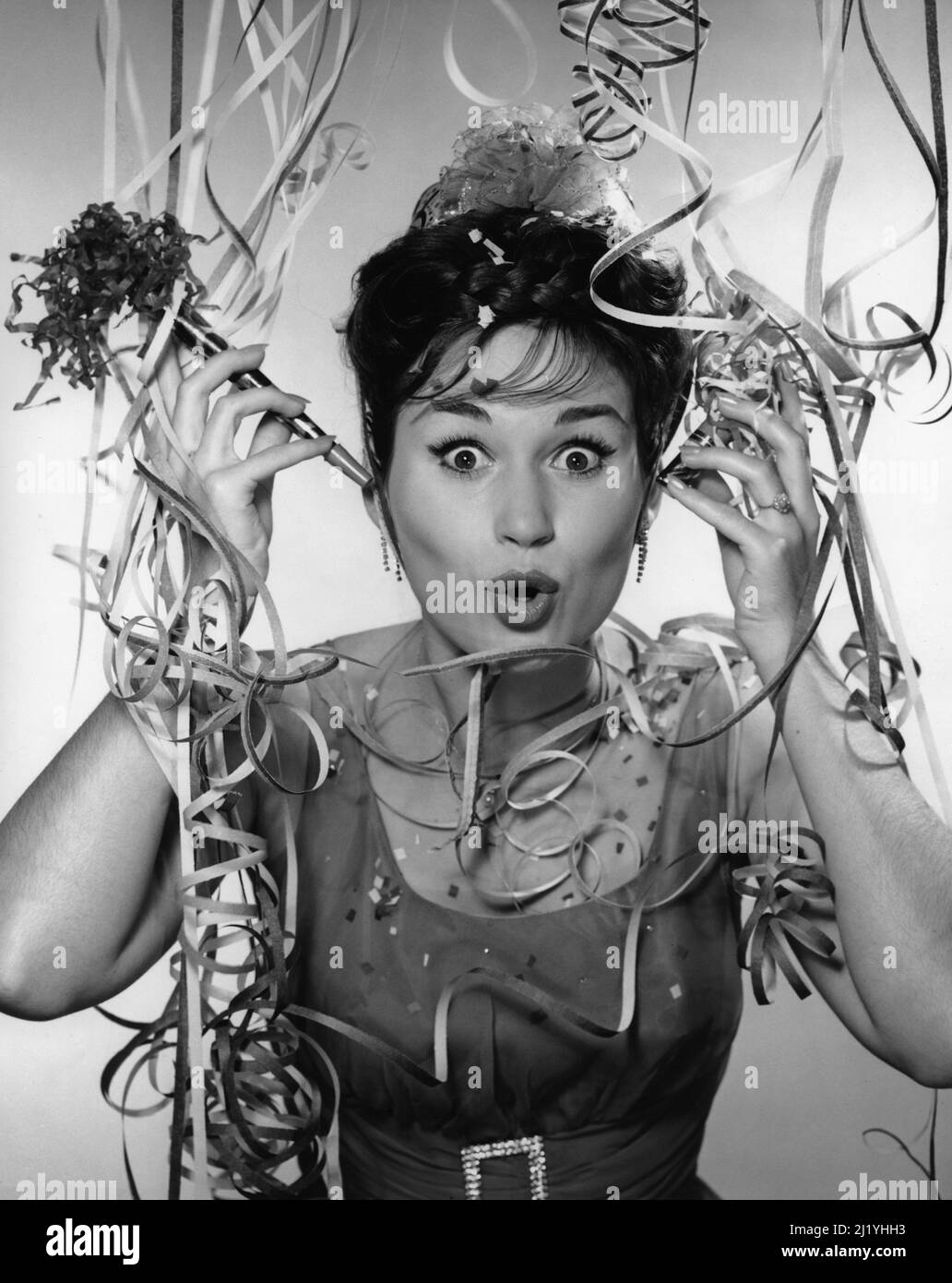 Woman with surprised look and streamers all around her celebrating New ...