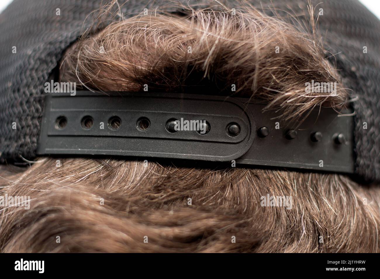 detail of the back of an adjustable cap on a light-color head of hair ...