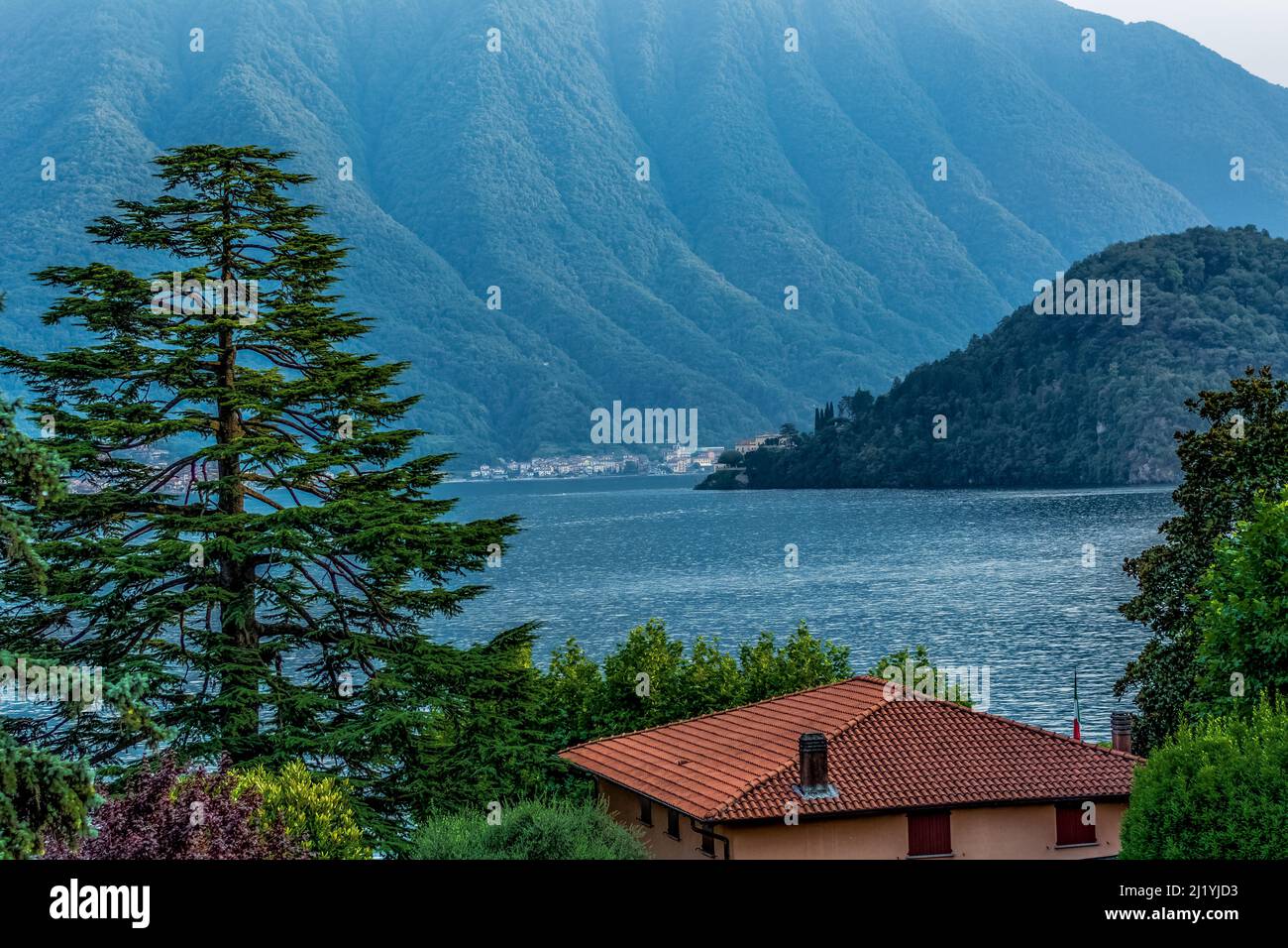 A beautiful scene of trees, houses in Lake Como, Italy with mountains ...