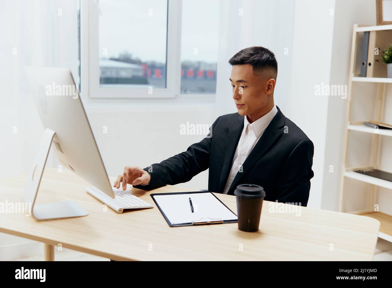Asian man sitting at a desk in front of a computer emotions ...