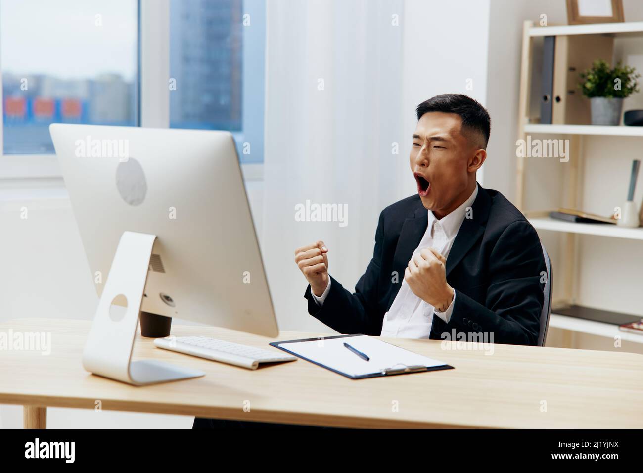 Asian man sitting at a desk in front of a computer technologies Stock ...