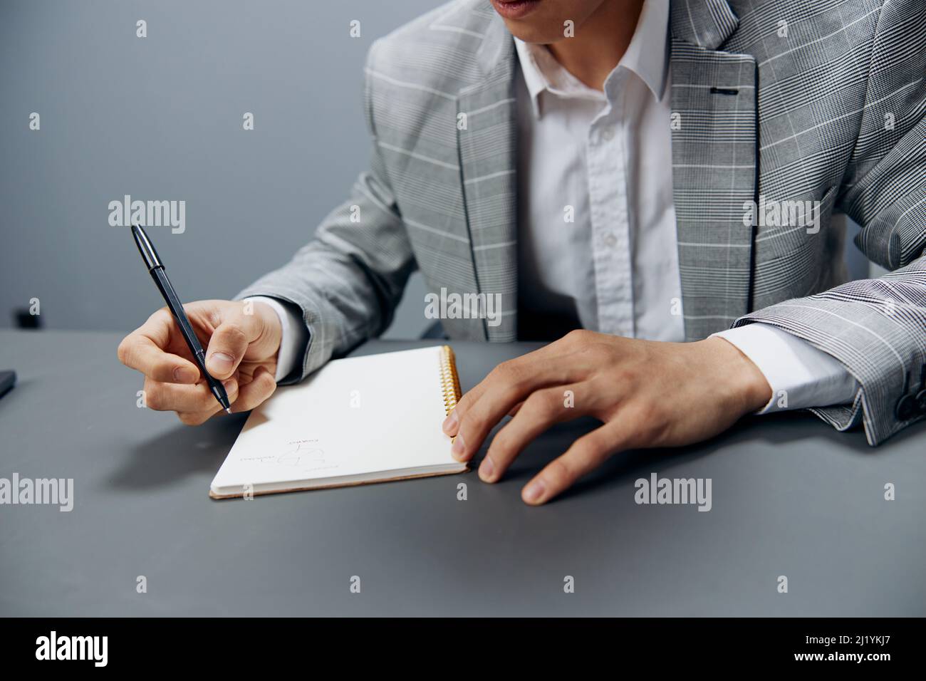 Asian man writing in a notebook laptop work at the desktop Gray ...