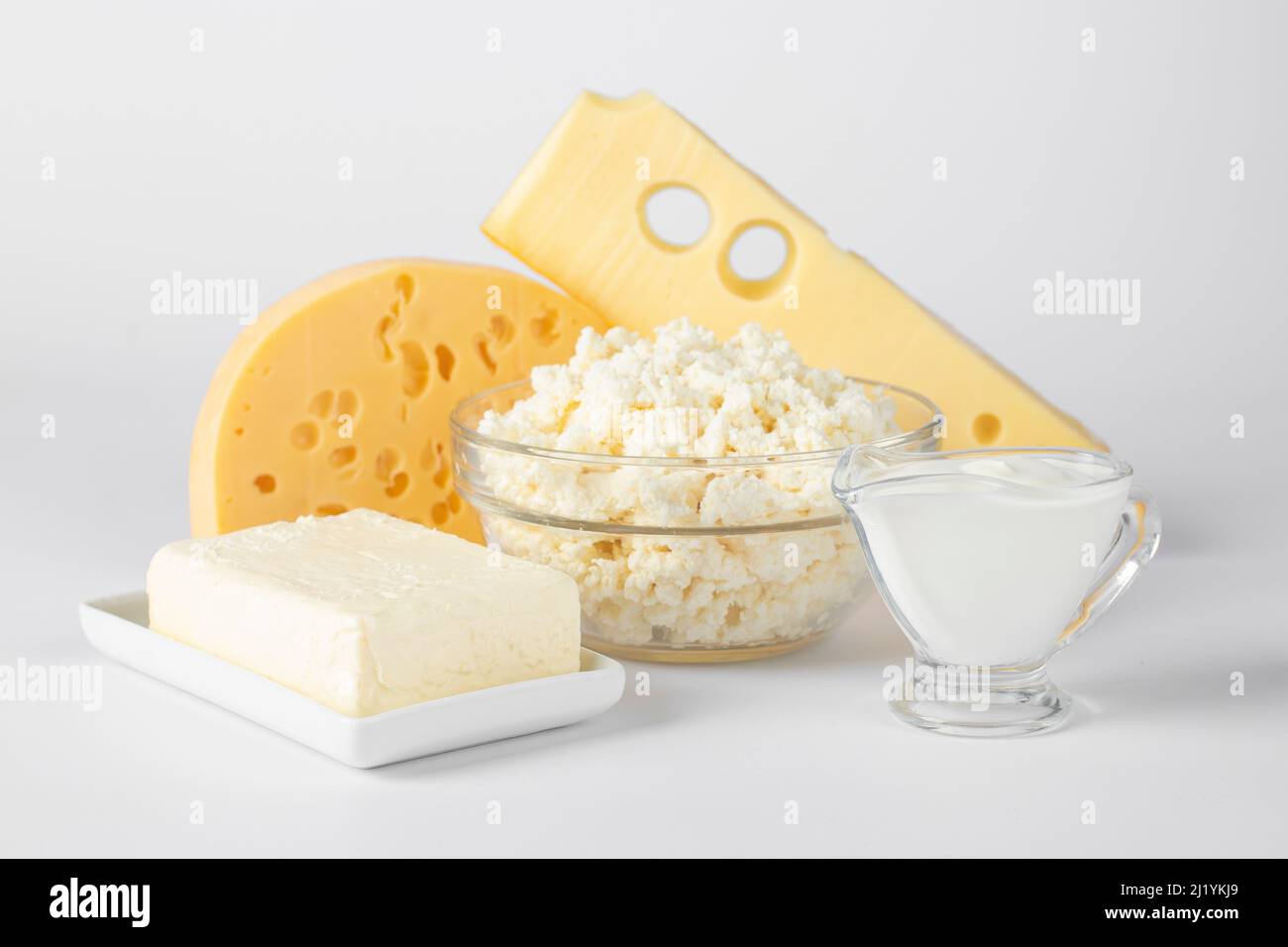 Hard cheese, cottage cheese, butter and sour cream on white background ...