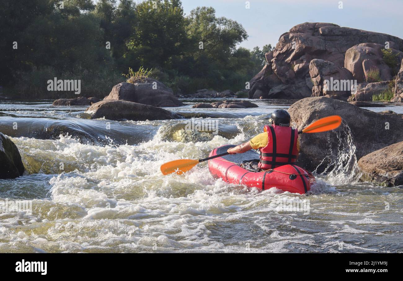A man rowing inflatable packraft on whitewater of mountain river ...