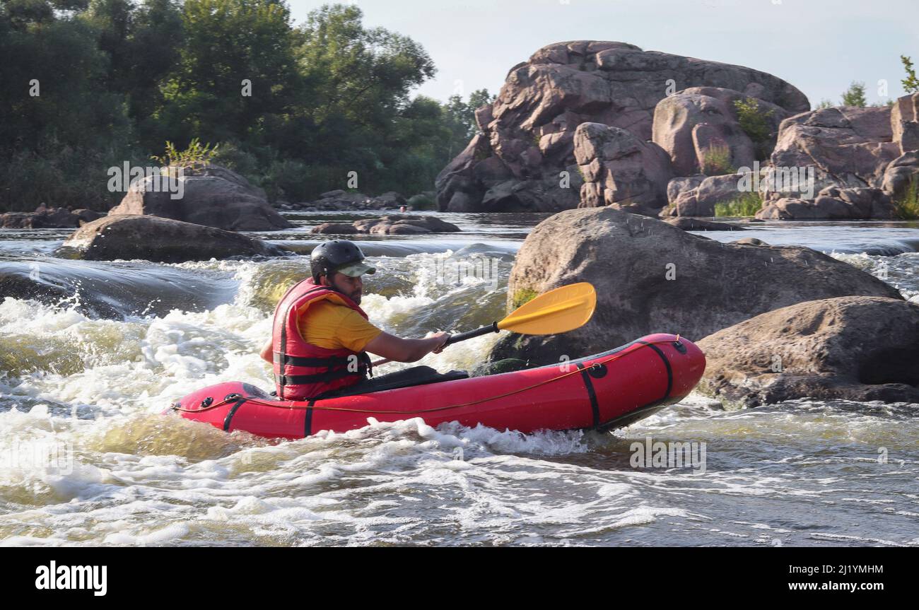 A man rowing inflatable packraft on whitewater of mountain river ...