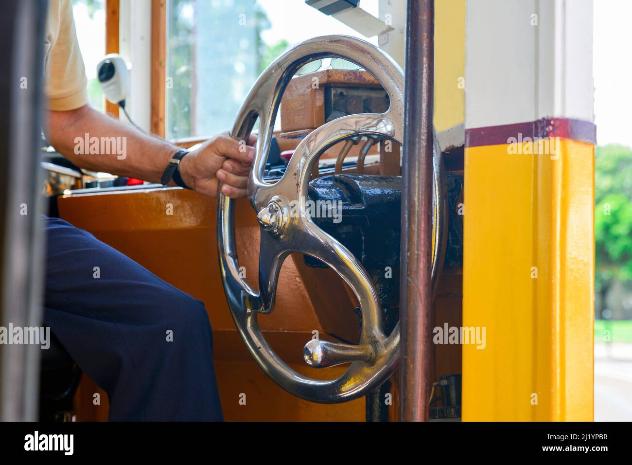 The tram driver holds a helm in a old famous yellow tramway in Lisbon ...