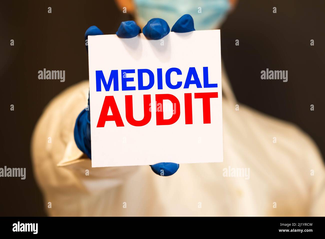 Doctor holding a business card with capital lettering MEDICAL AUDIT in ...