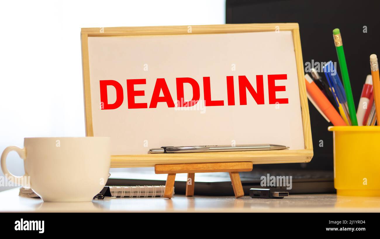 Deadline word written on a post note and hanged on the cork-board with ...