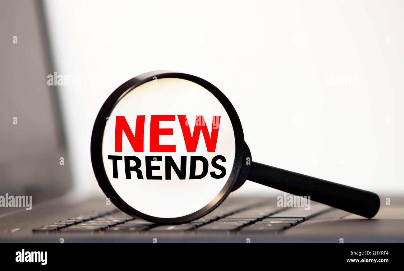 NEW TRENDS text written on magnifying glass. Main trend of changing ...