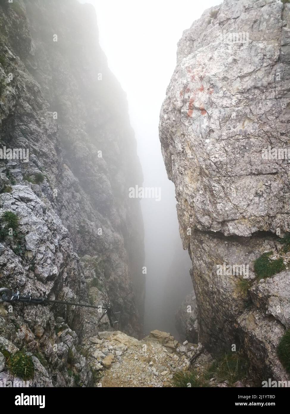 A vertical shot of steps going down between cliffs on a foggy ...