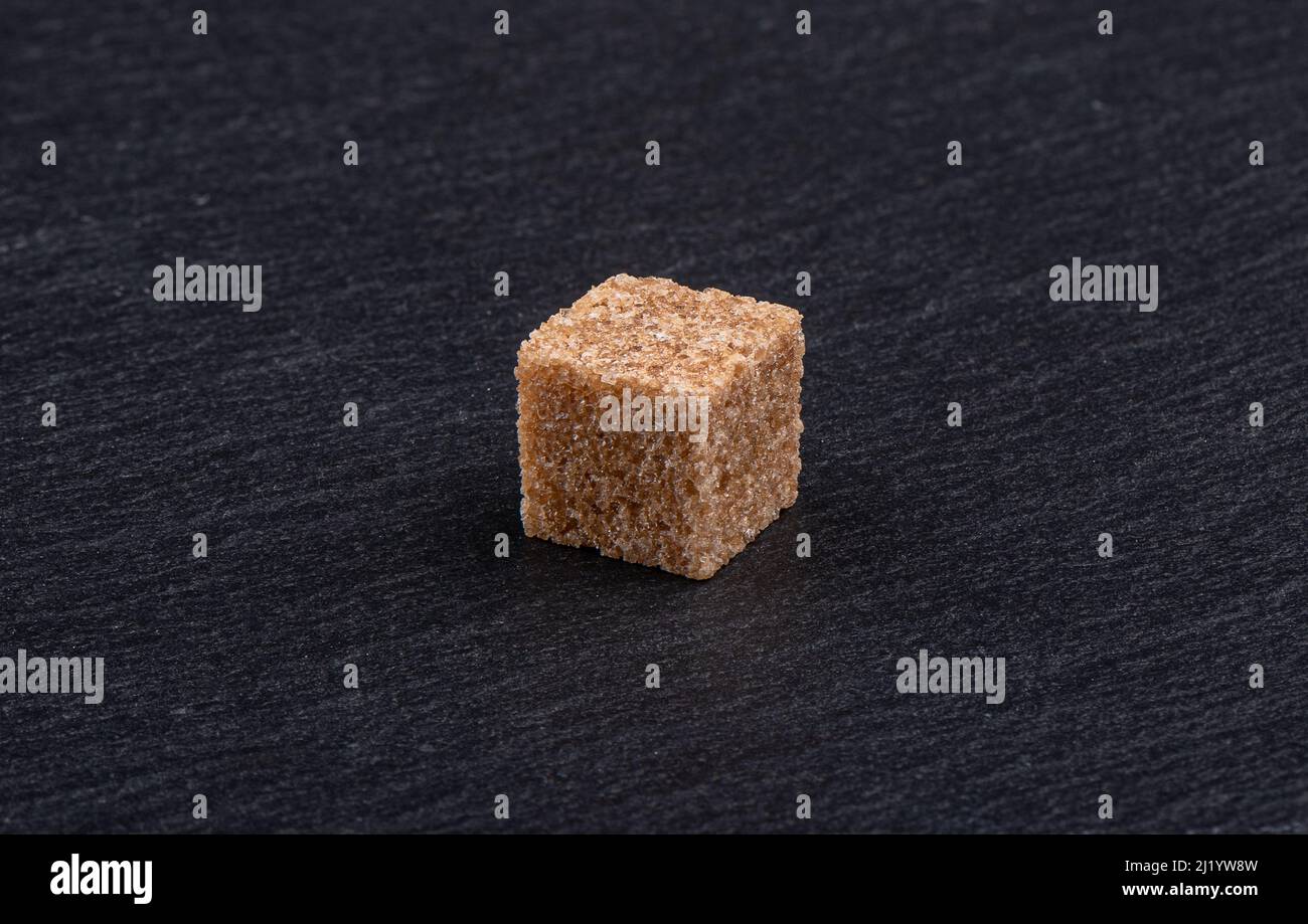 Cube of brown refined cane sugar on a stone background. Copy space ...